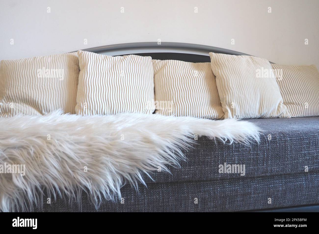 Gray sofa with rough upholstery fabric boucle and white decorative ...