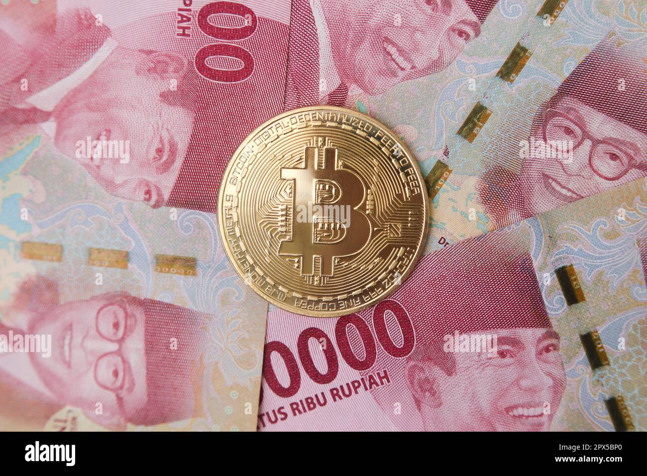 Bitcoin placing on the top of one hundred thousand rupiah bank note ...
