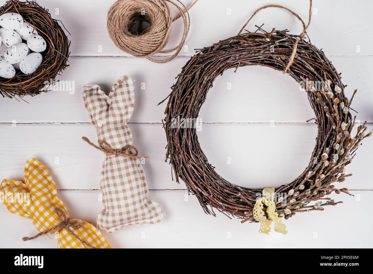 Easter crafting woven willow wreath with tape bow. White planking wall ...