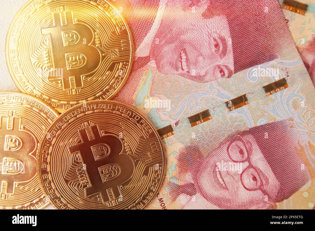 Bitcoin placing on the top of one hundred thousand rupiah bank note ...