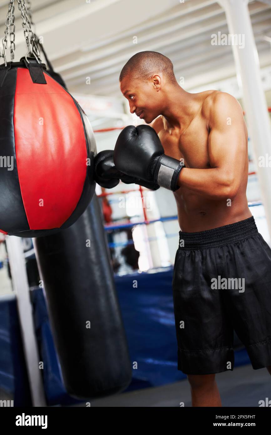 Putting the hard hours in. An african american boxer practicing with a ...