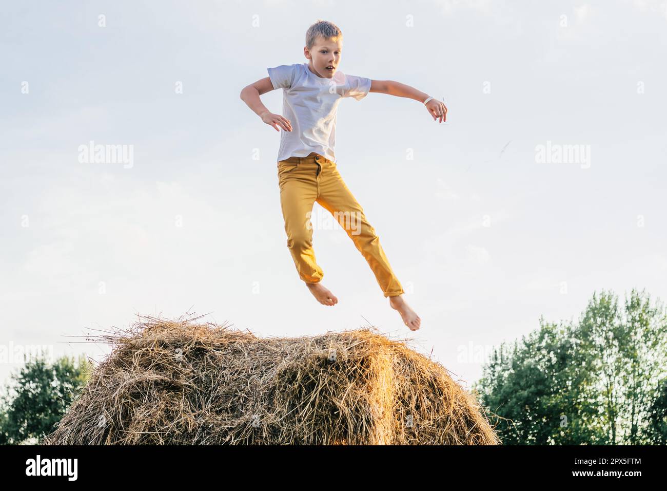 Child jumping on hay in hi-res stock photography and images - Alamy