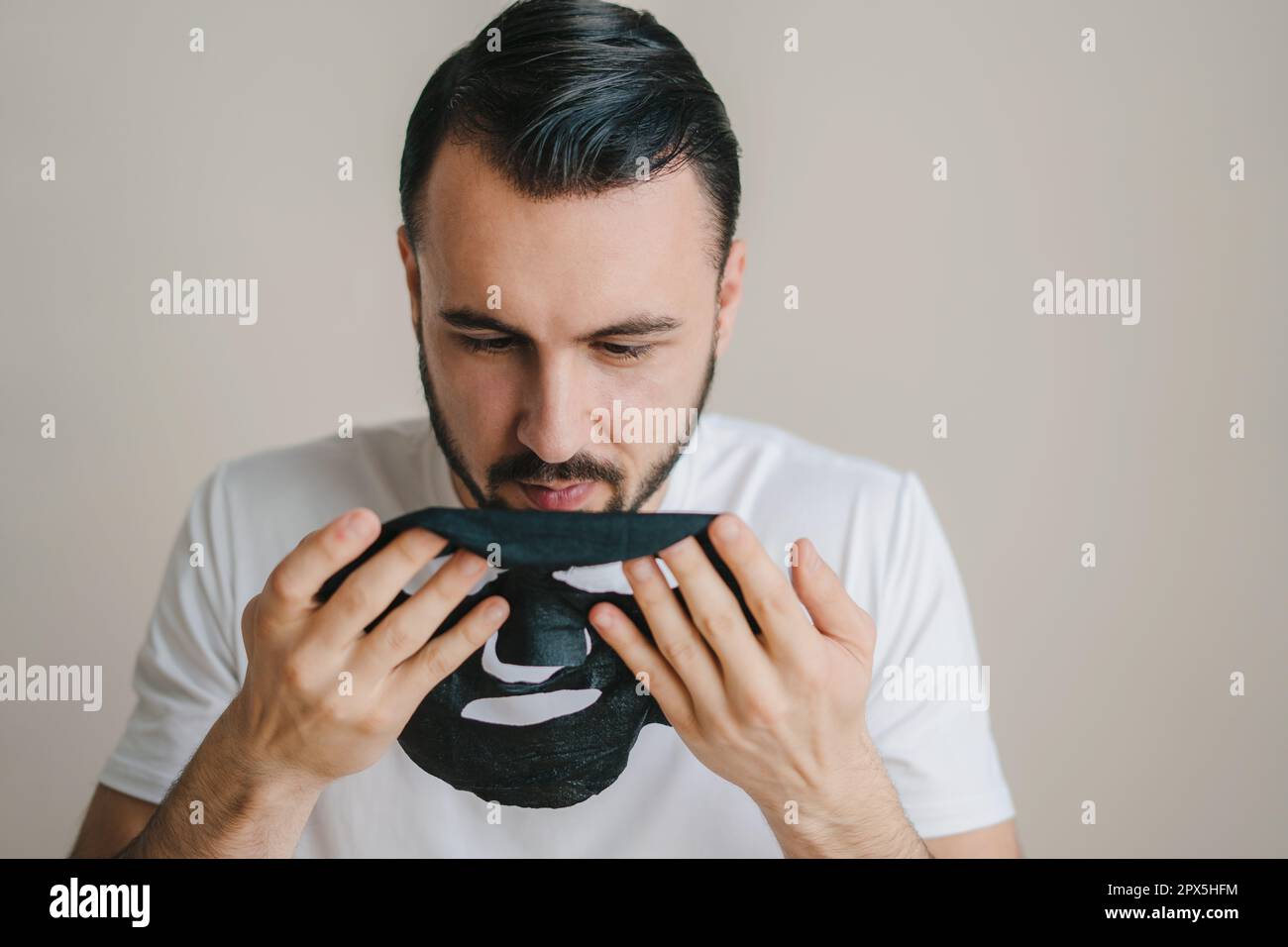 Caucasian man applying black mask on face with well groomed man getting ...