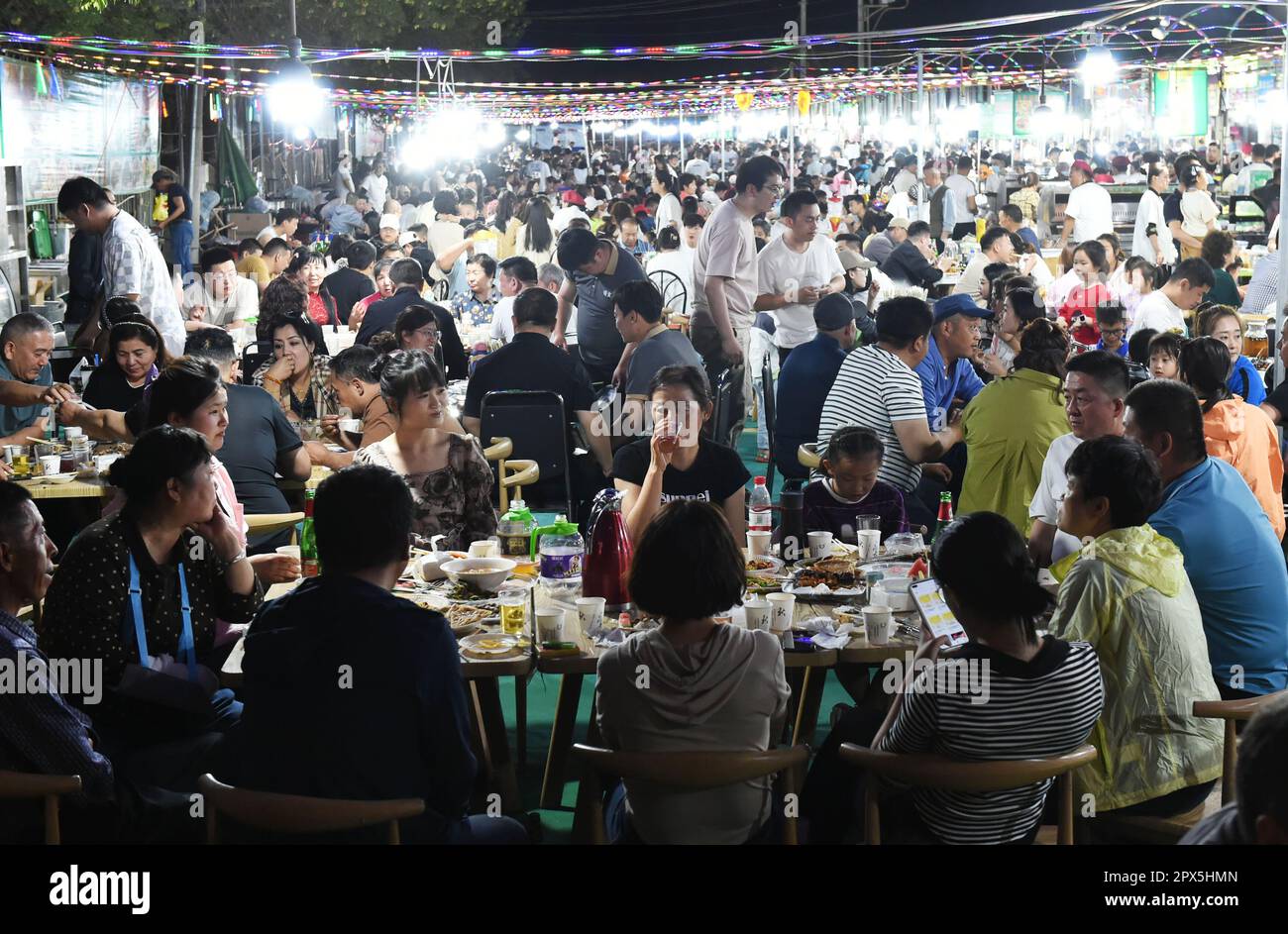 TURPAN, CHINA - MAY 1, 2023 - Tourists enjoy delicious food at a night ...