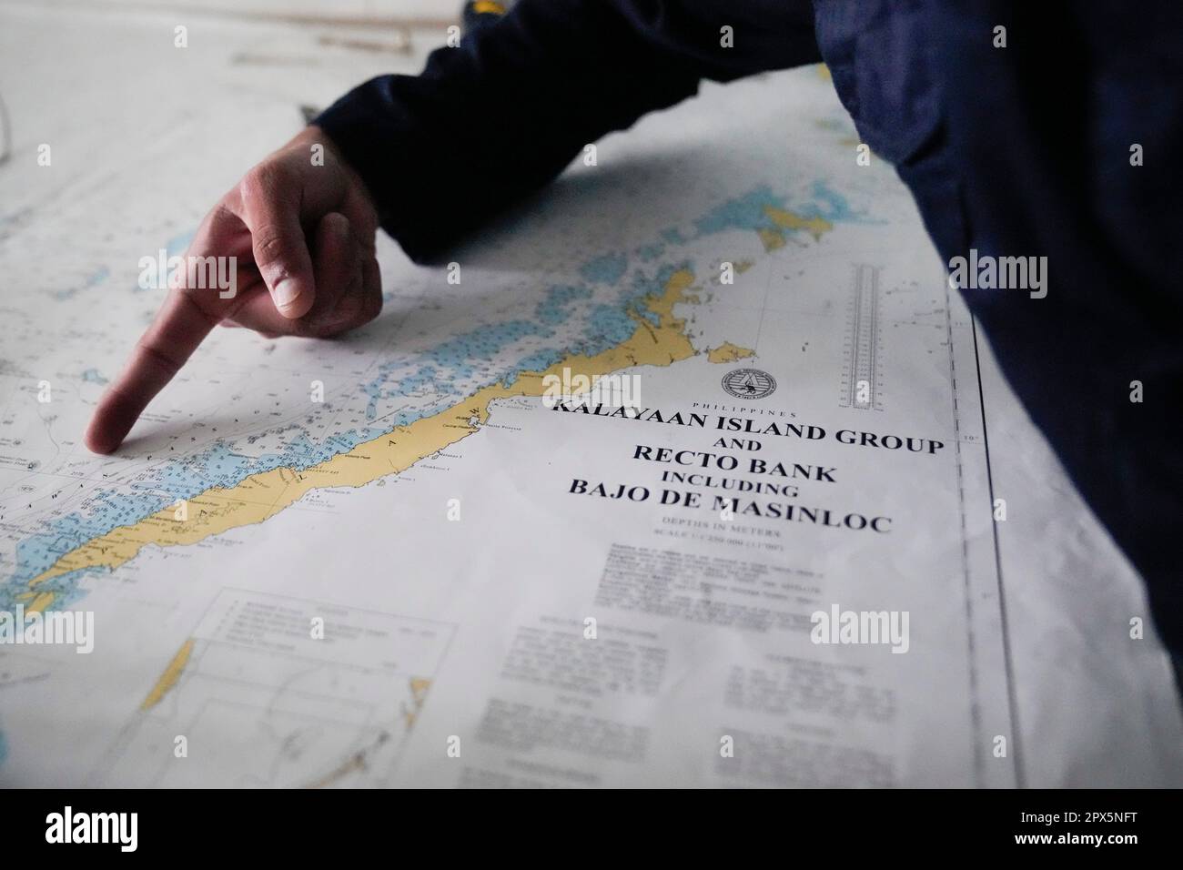 A member of the Philippine Coast Guard points at the map onboard the ...