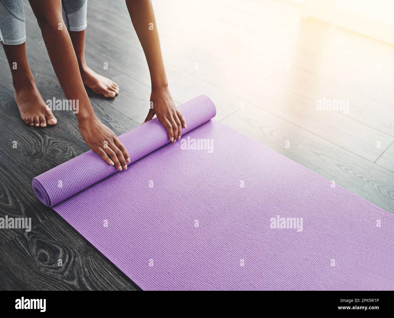 I go everywhere with my yoga mat. an unrecognizable woman rolling up ...