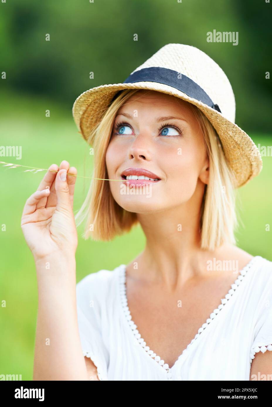 Relaxing outdoors. Attractive young woman smiling while wearing a hat ...