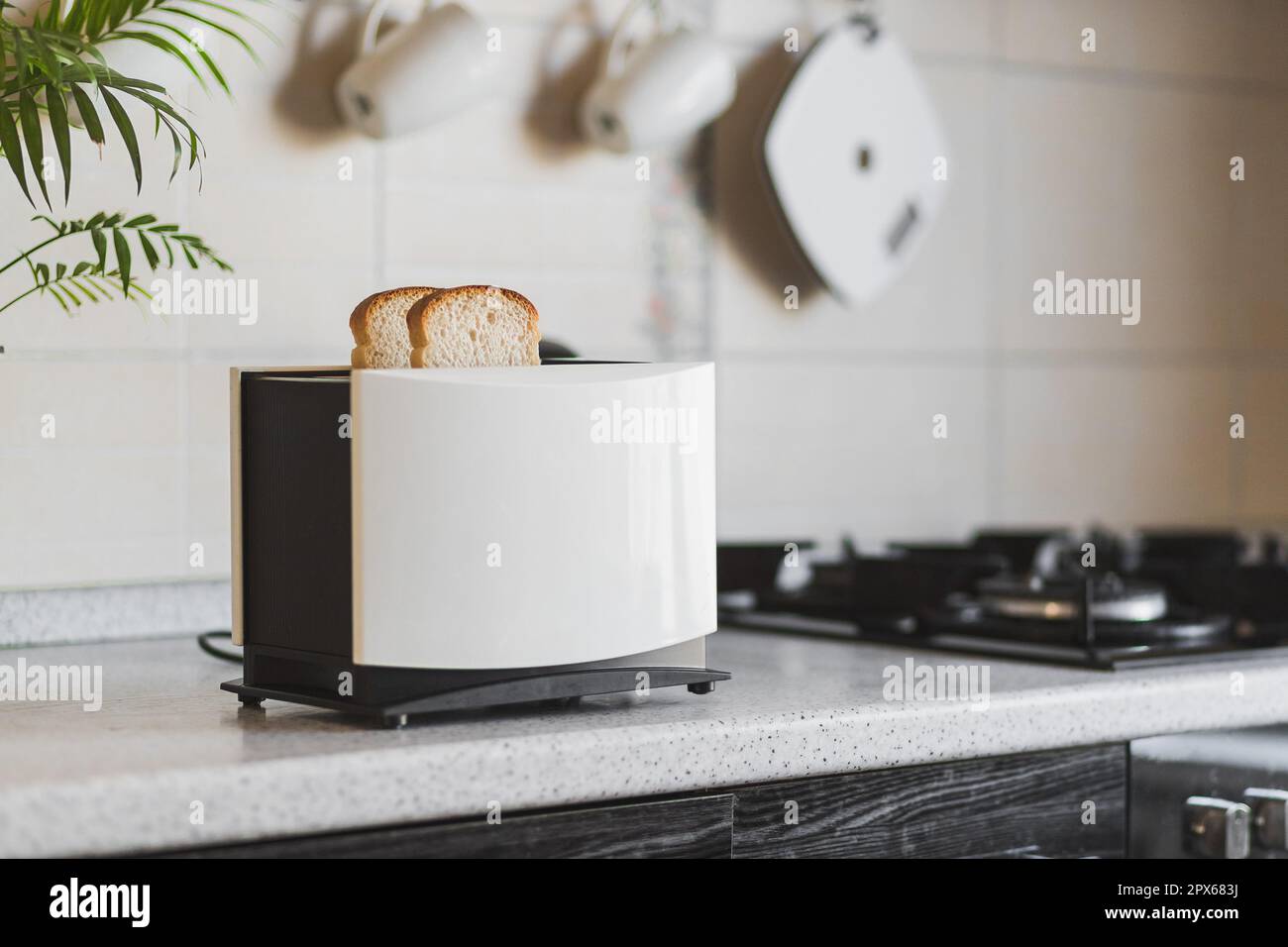 White toaster with sliced bread stands on the work surface of the ...
