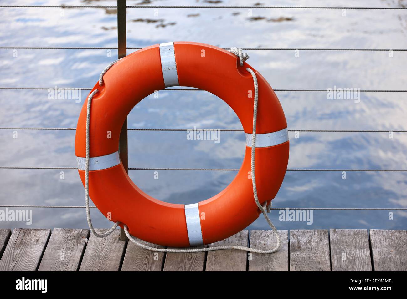 Orange lifebuoy on a beach. Safety on a water, life ring on wooden pier Stock Photo - Alamy