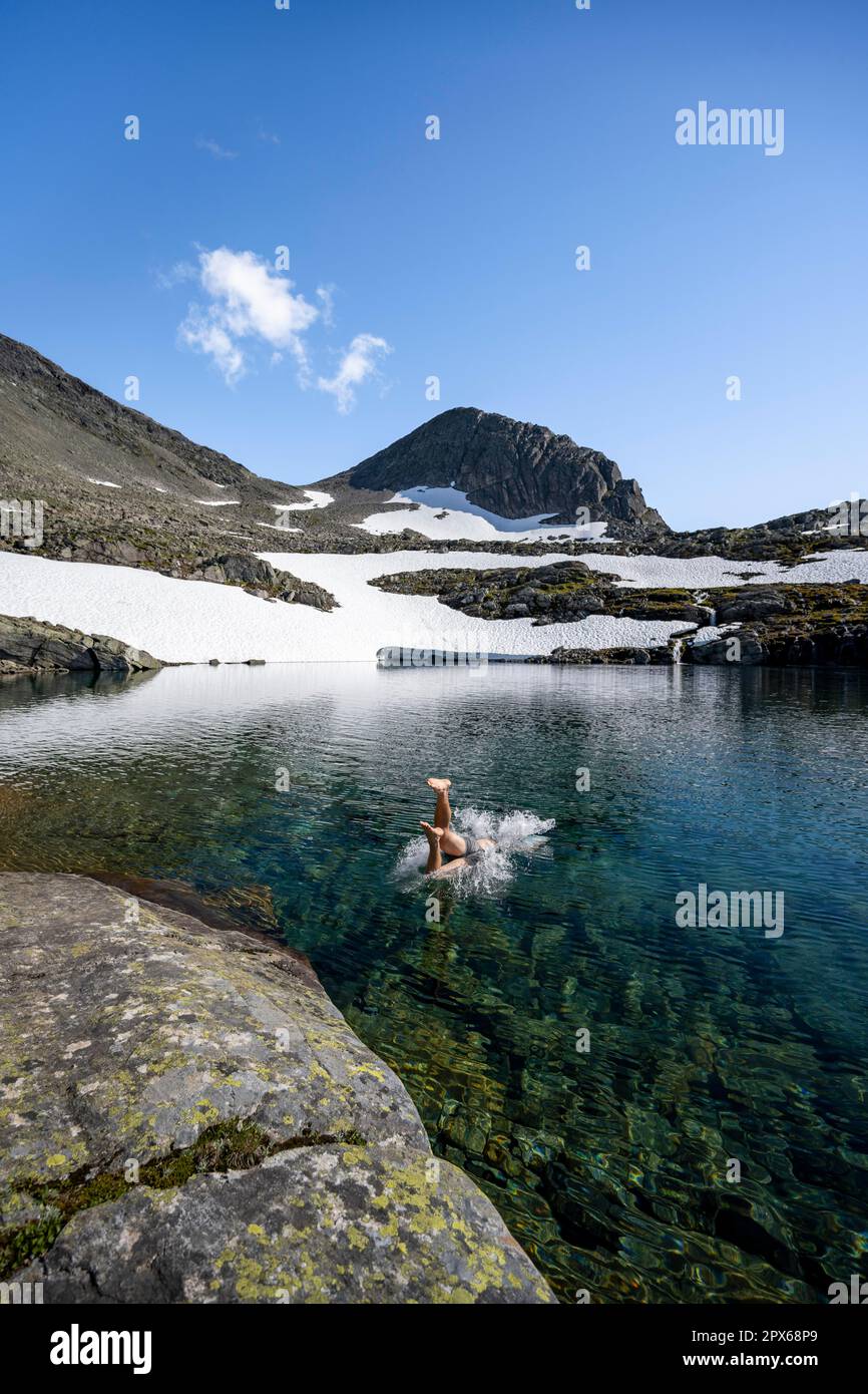 Young man jumps into a mountain lake, Skalavatnet, ascent to the summit ...