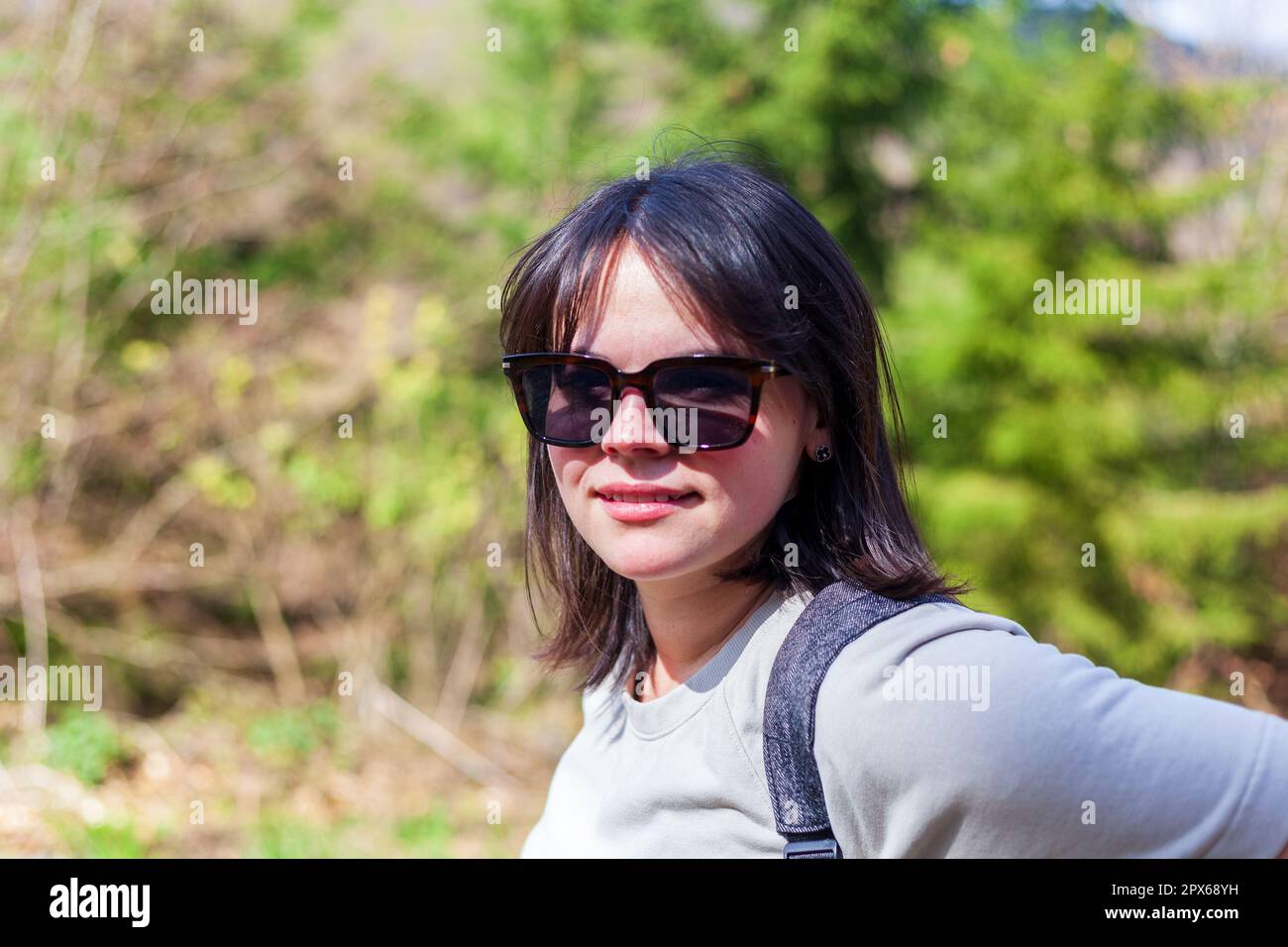A girl with sunglasses is enjoying the outdoors on a hiking trail. Her ...