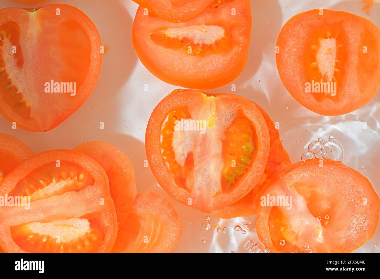 Tomato close-up in liquid with bubbles. Slices of red ripe tomato in ...