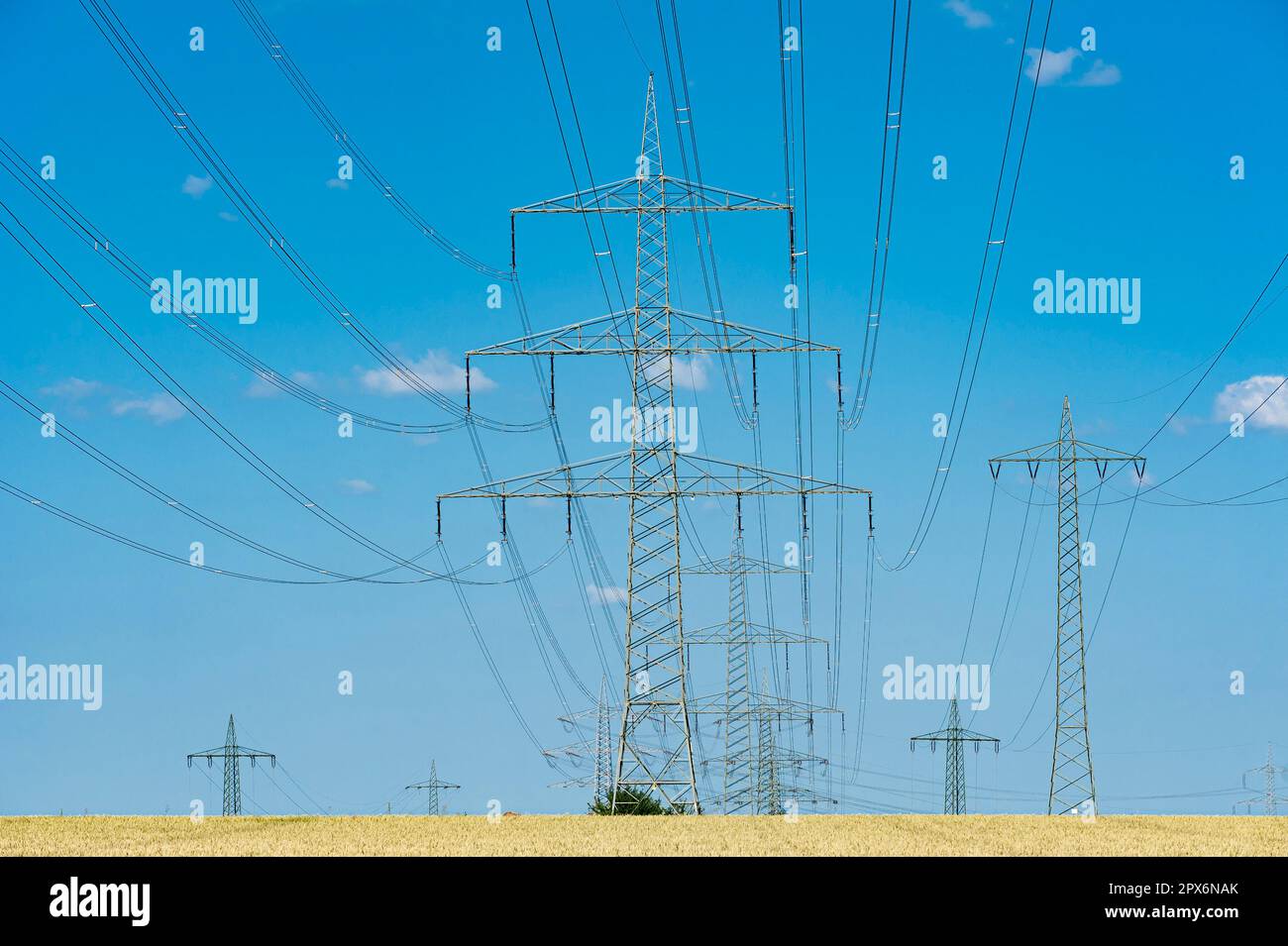High voltage pylons with overhead lines against blue sky Stock Photo ...