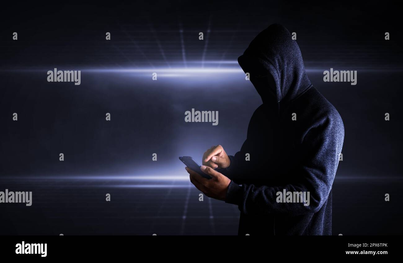 Hacker Using Smartphone. Men in black clothes with hidden face looks at smartphone Stock Photo ...
