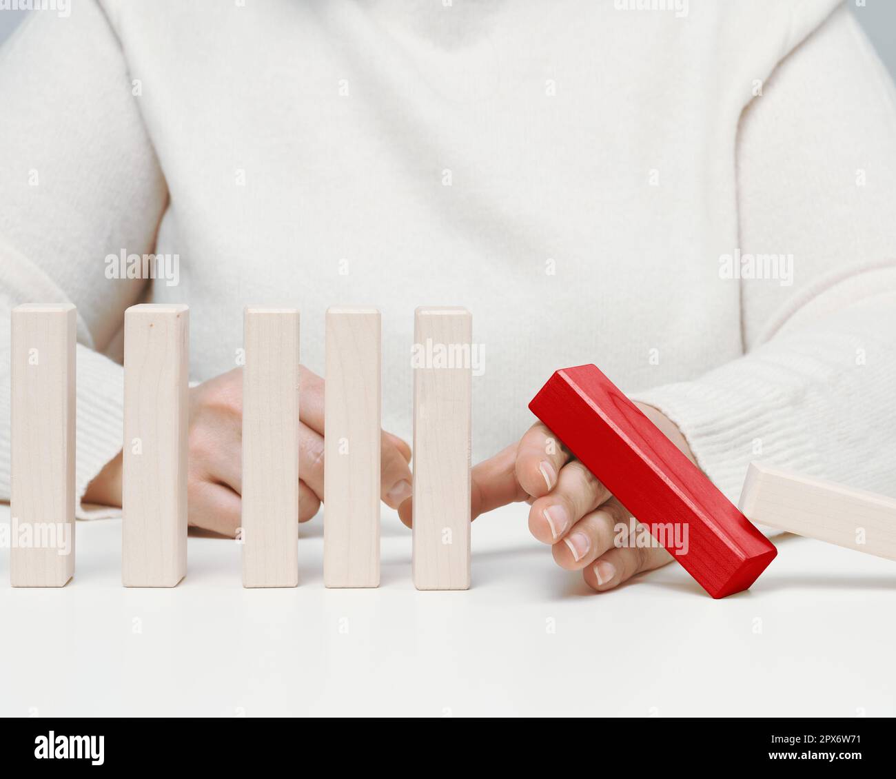 Hand stops the fall of wooden blocks on a white background. Concept of ...