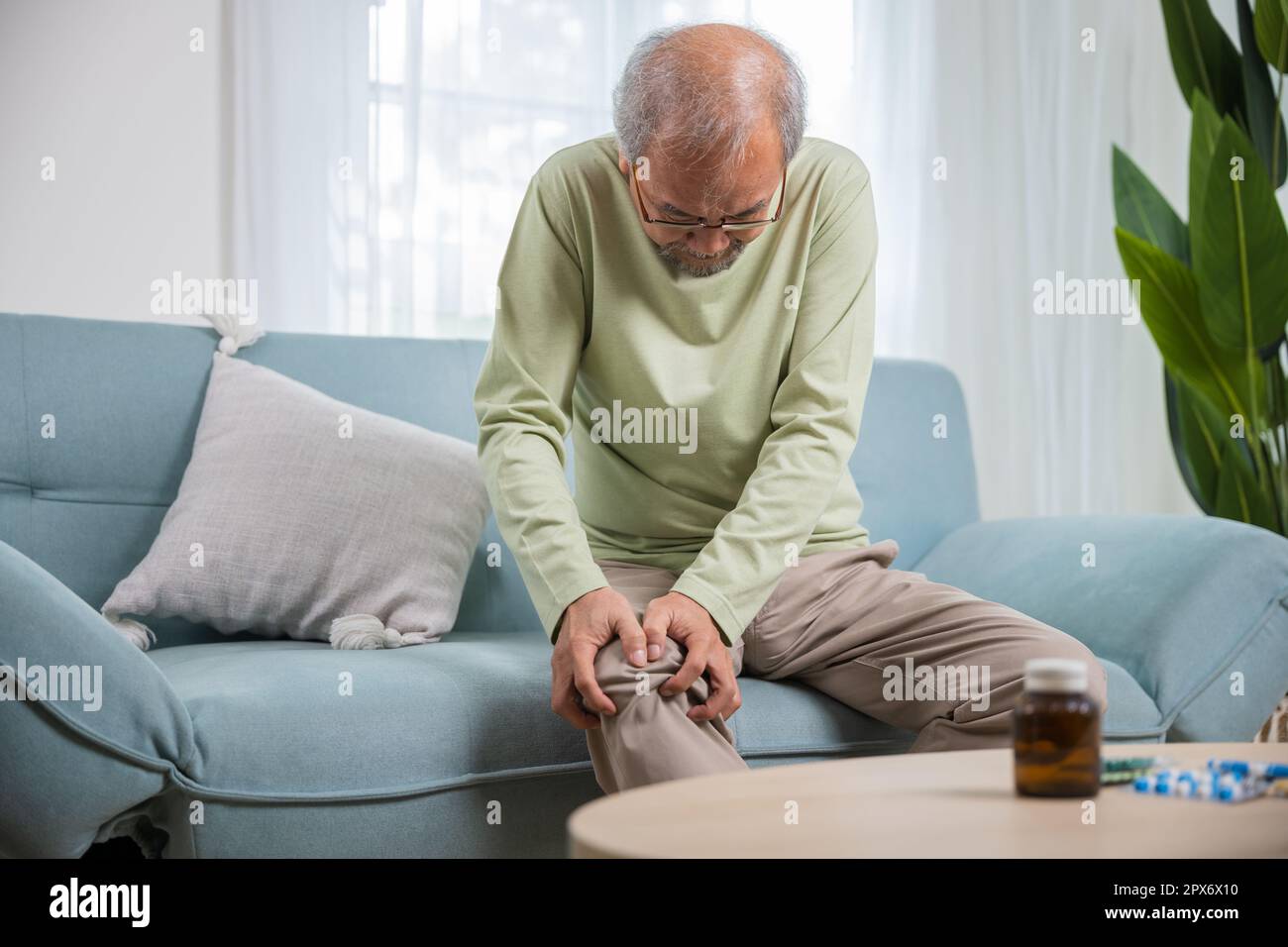Old man suffering from knee joint pain on sofa living room, bone pain ...