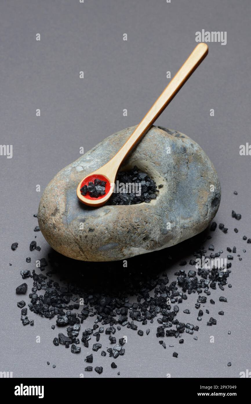 Black Hawaiian salt on spoons and in hollowed stone, sea salt with ...