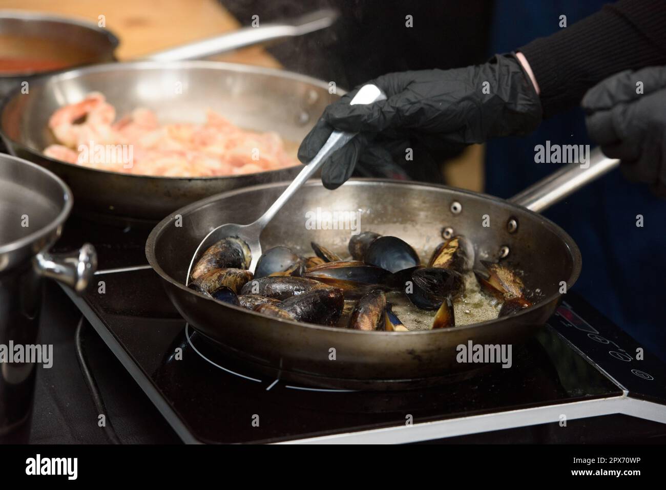 the chef in the restaurant is frying mussels in a steel pan Stock Photo ...