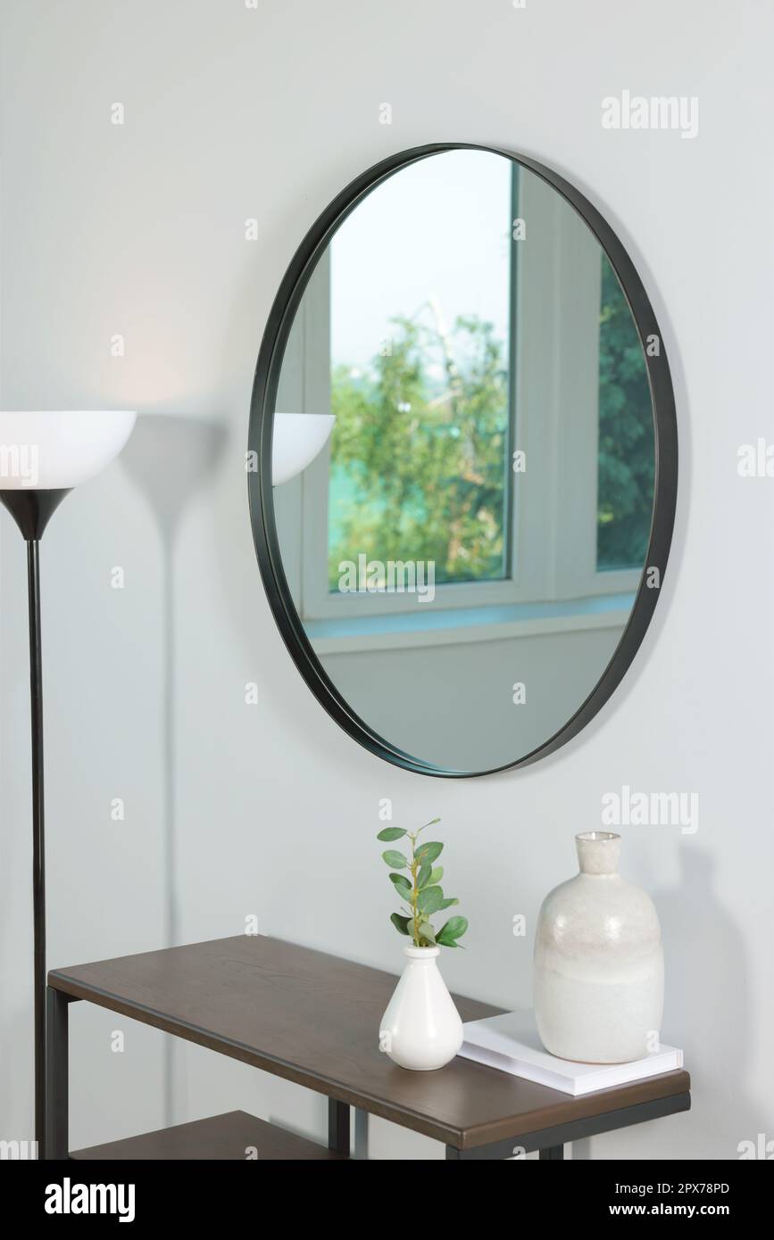 Stylish round mirror on white wall over table in room Stock Photo - Alamy