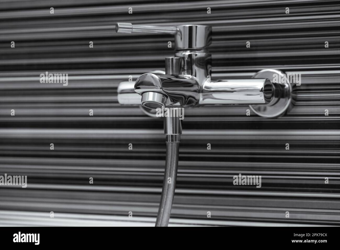 Shiny bath water tap installed on black and white wall Stock Photo - Alamy