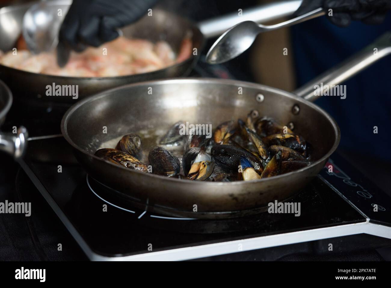 the chef in the restaurant is frying mussels in a steel pan Stock Photo ...
