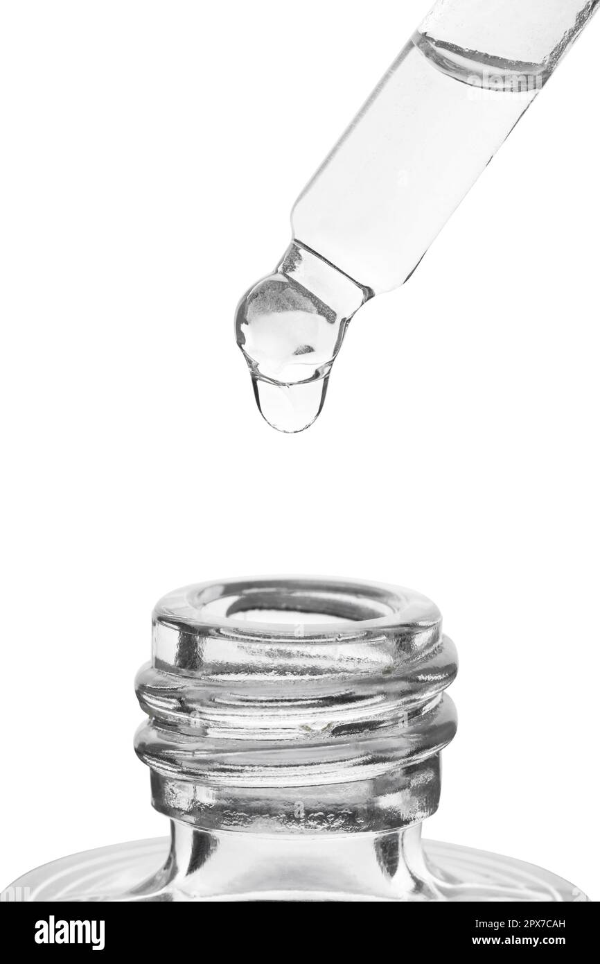 Dripping clear facial serum from pipette into glass bottle on white ...