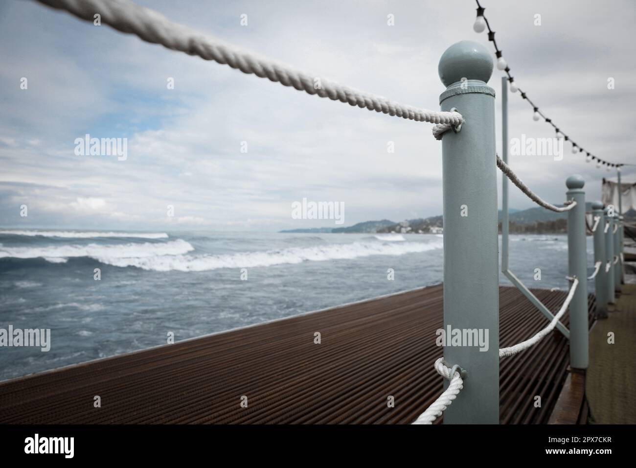 Picturesque view of sea with waves behind pier fence Stock Photo - Alamy