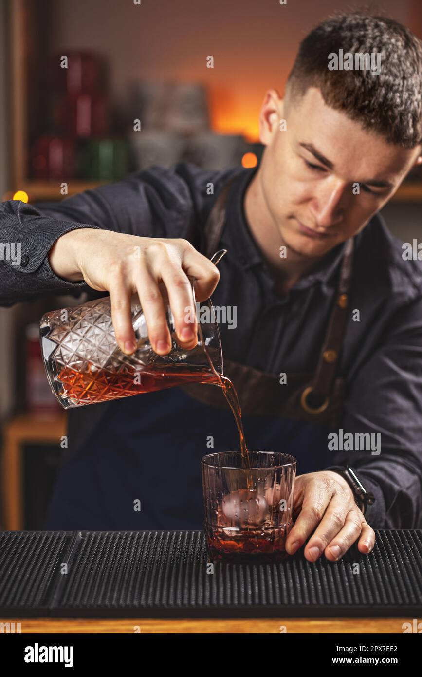 Bartender making negroni cocktail in glass on bar counter Stock Photo ...