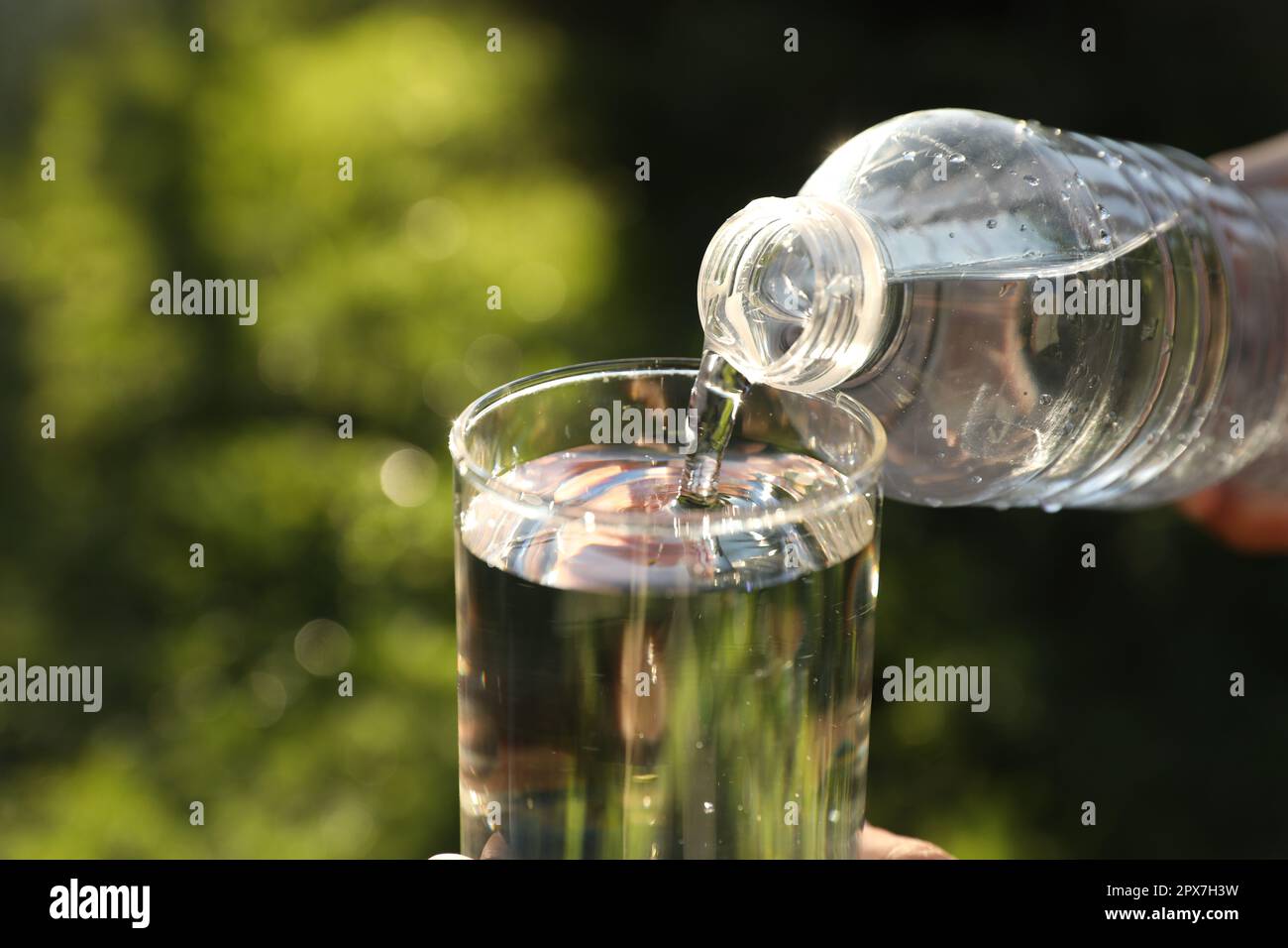 Pouring fresh water from bottle into glass outdoors, closeup Stock ...