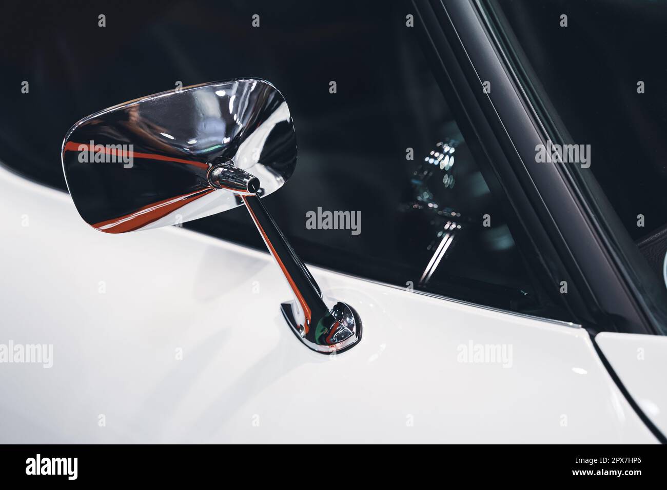 side view detail closeup of chrome rear mirror on white car with ...