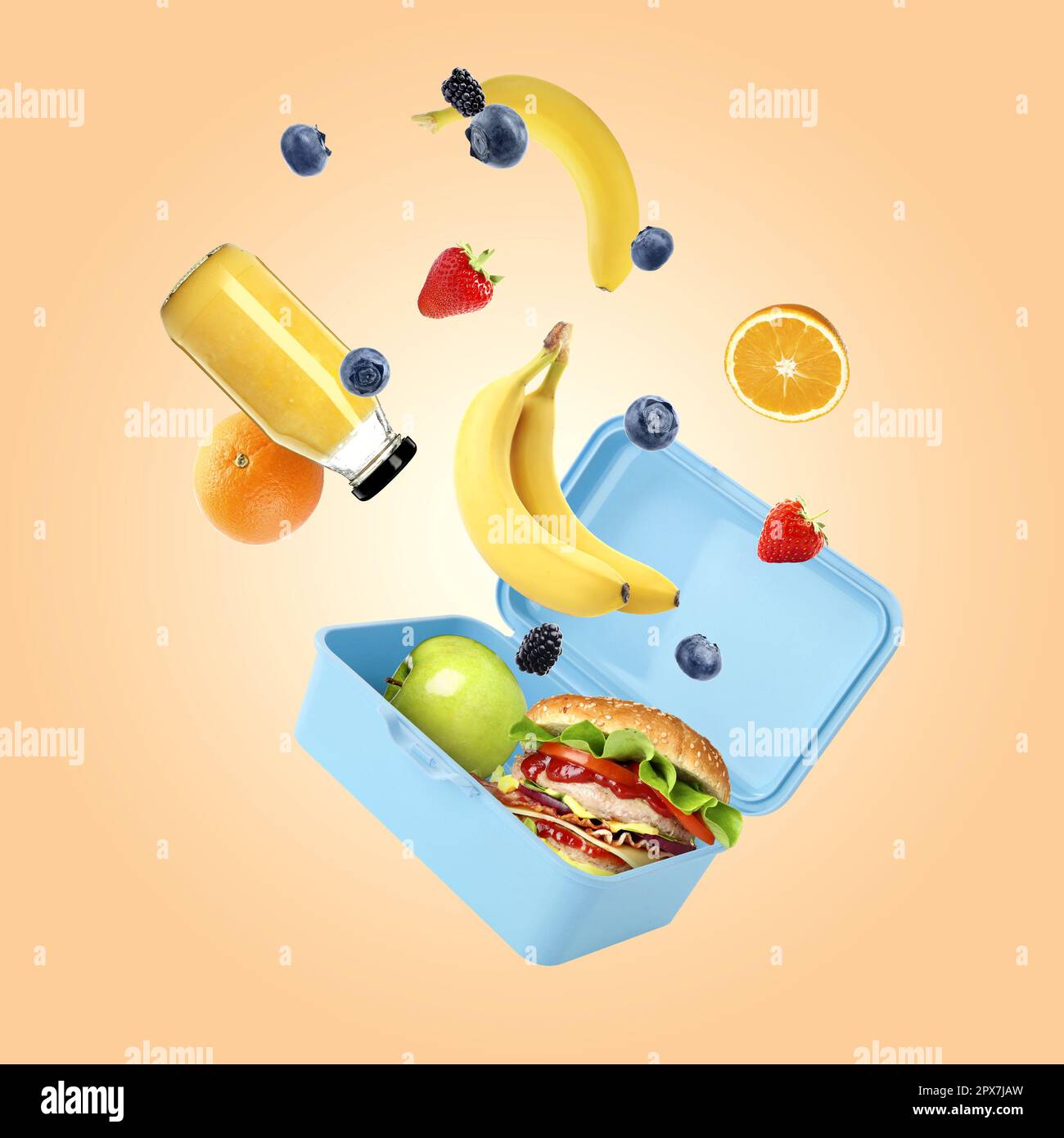 Different fresh food falling into lunch box on orange background ...
