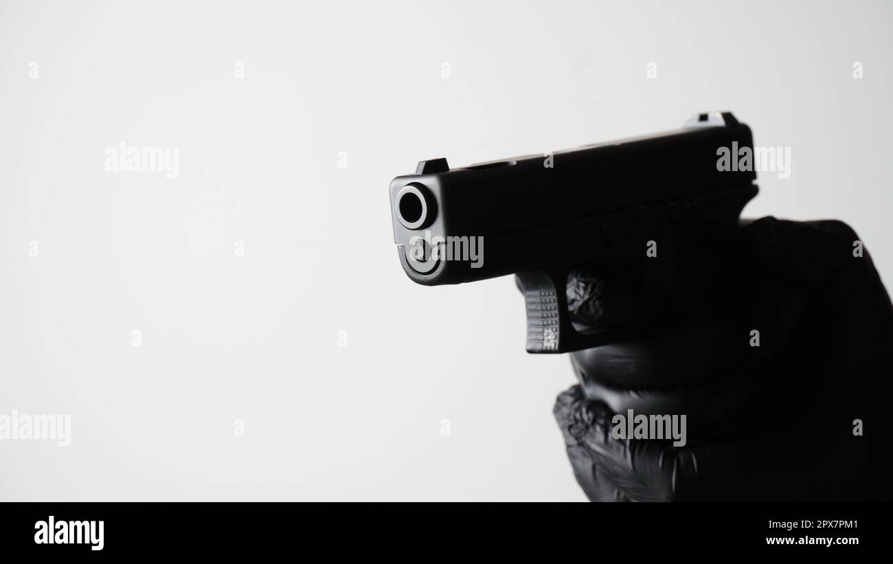 Hands in black gloves holding pointing gun. Focus on barrel of gun ...