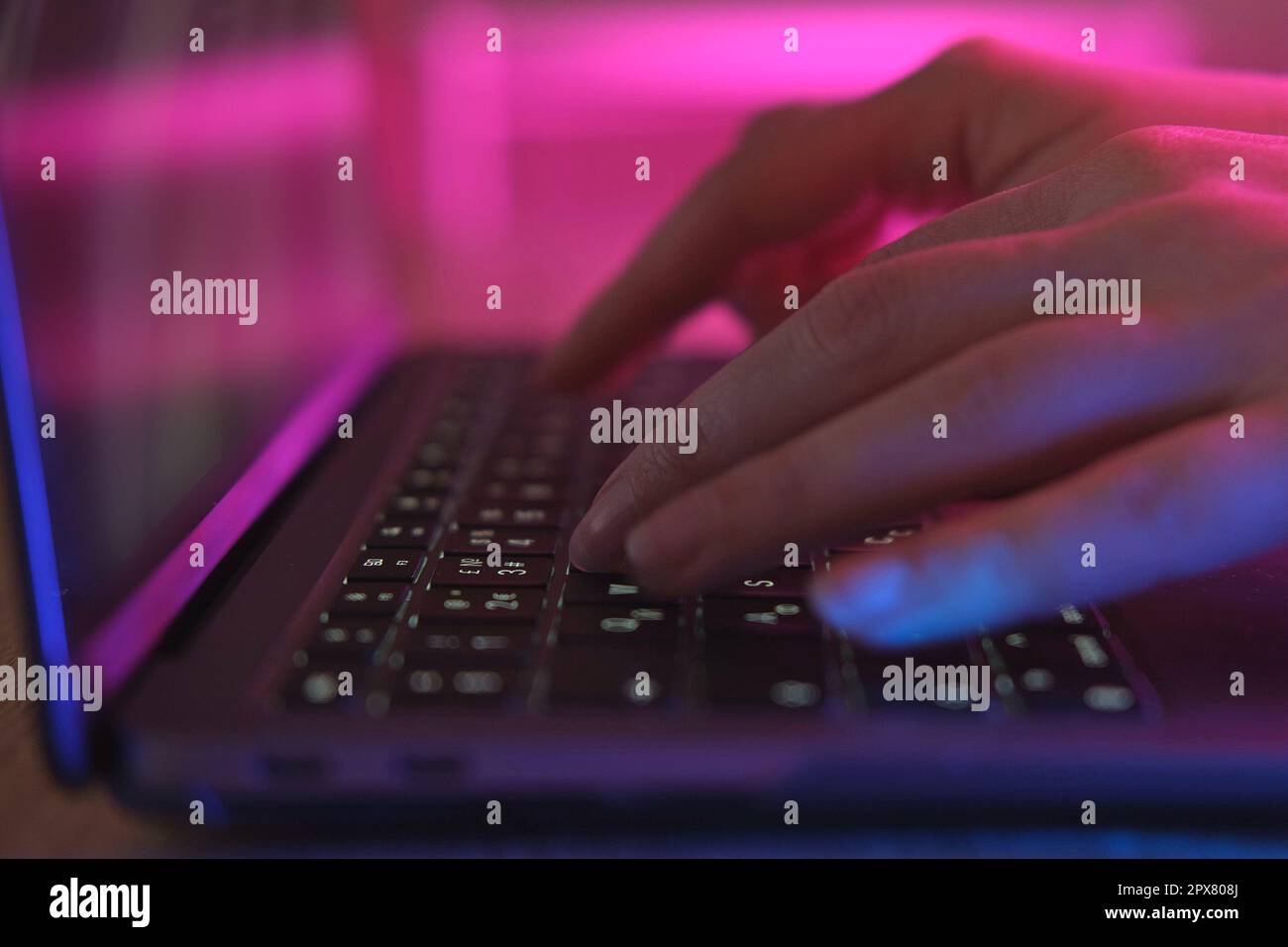 Person typing at laptop computer at night. Female uses keyboard, shakes ...