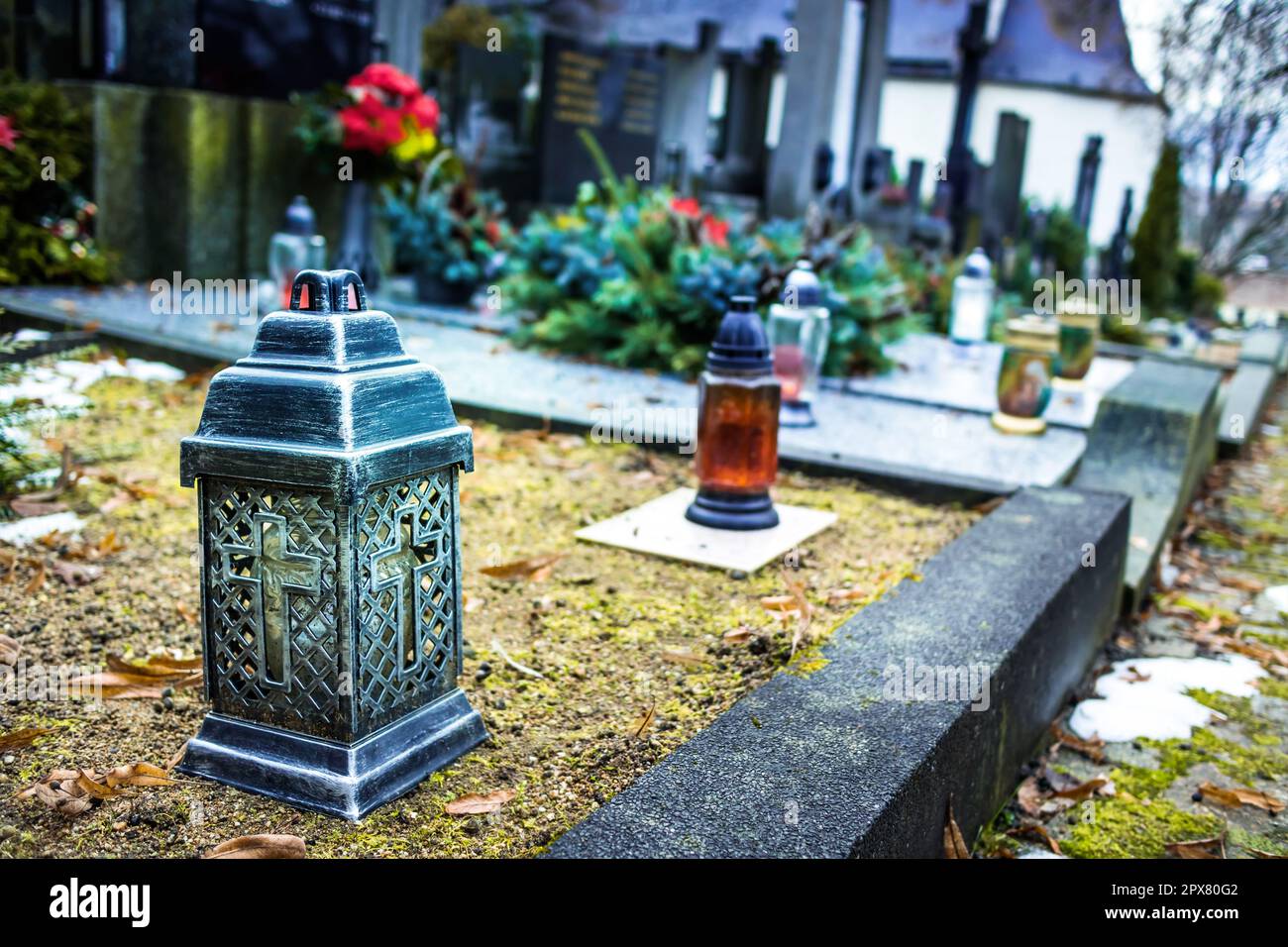 Candle lantern at grave in cemetery. Grief and paying respect for dead person. Tombstones and a ...