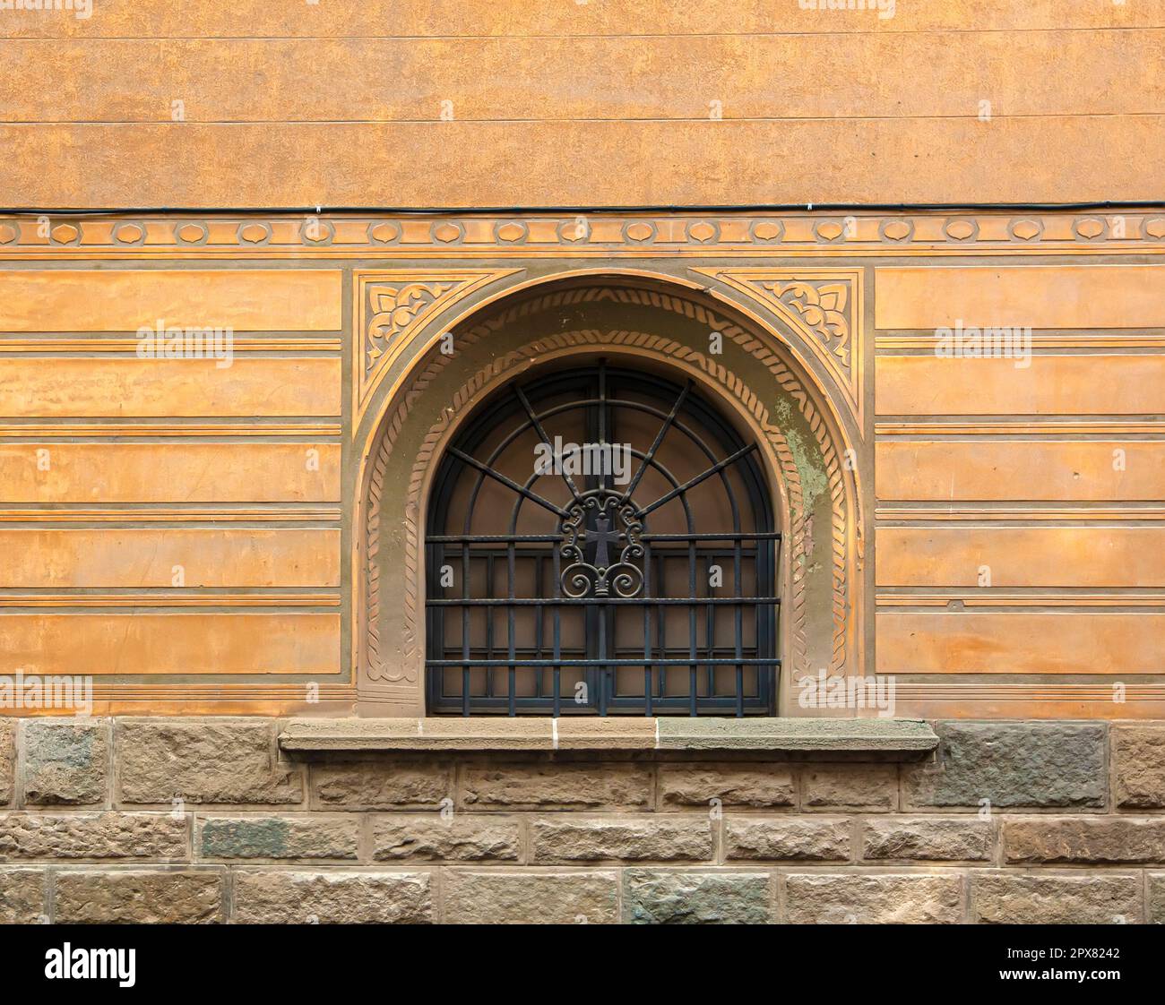 Figured metal lattice with a cross on a window on a stone wall Stock ...