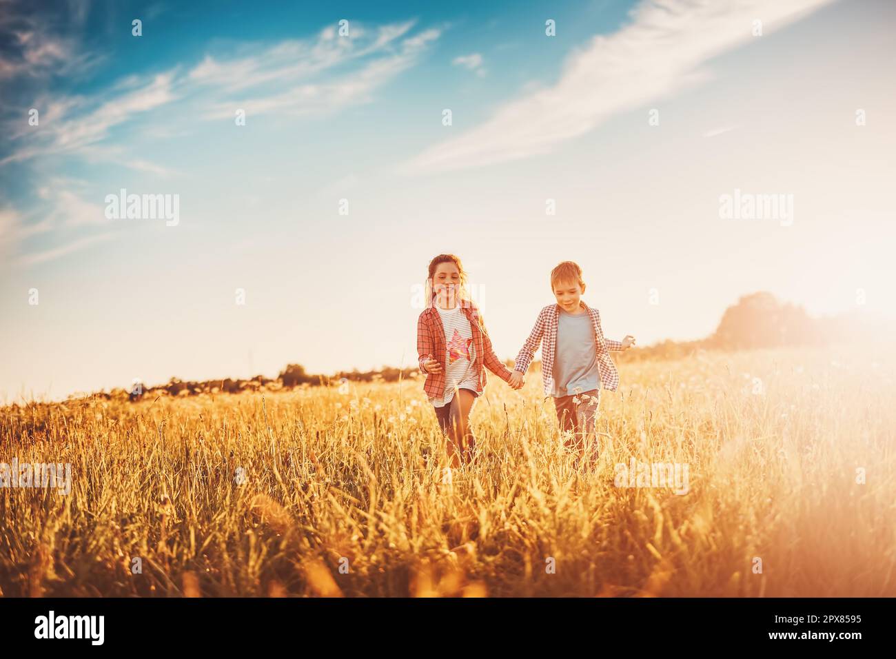 Two children running on the summer field by holding hands. Concept of ...