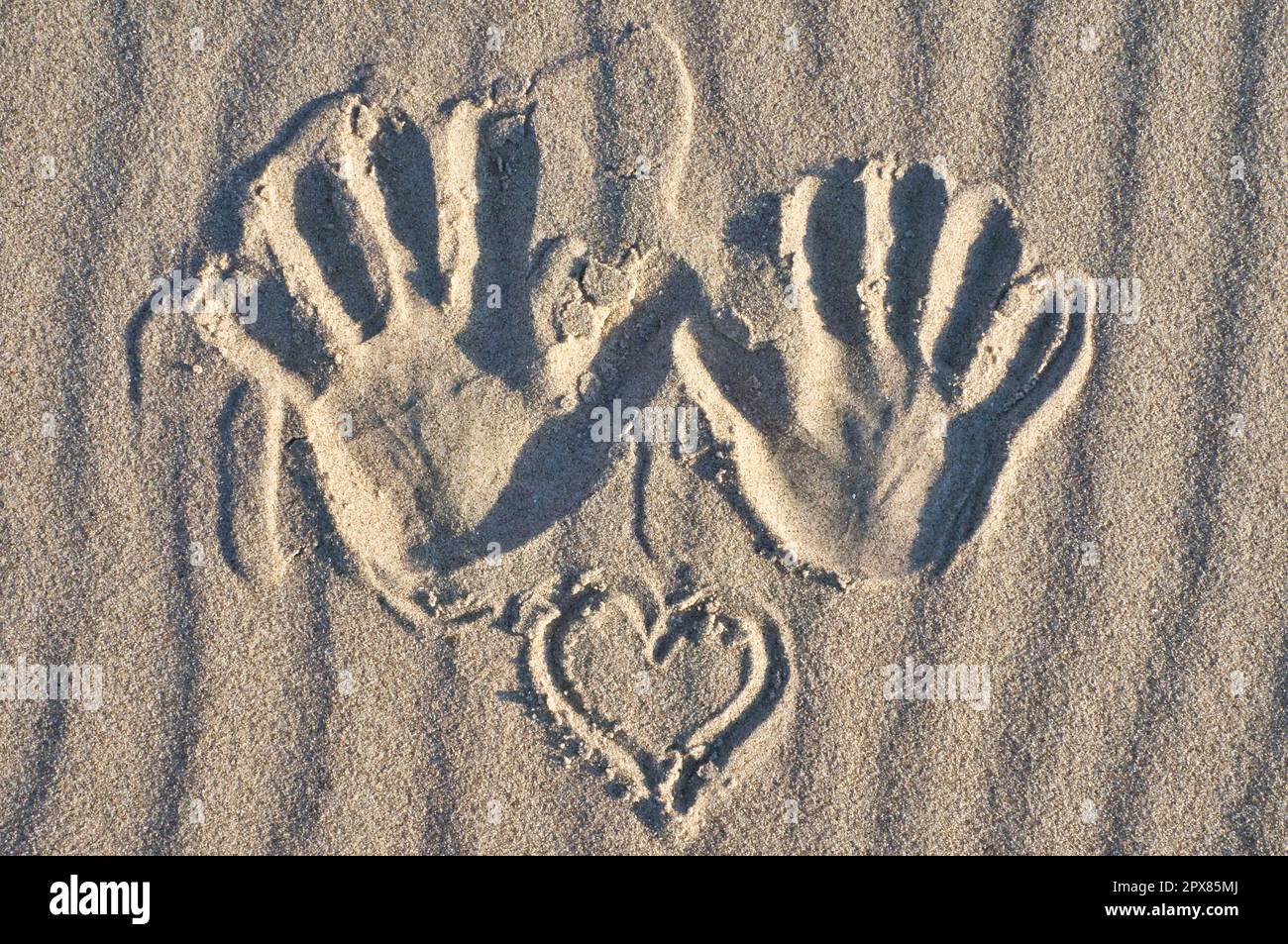 Hand print with heart in sand on beach. Corrugated sand. Still life on ...