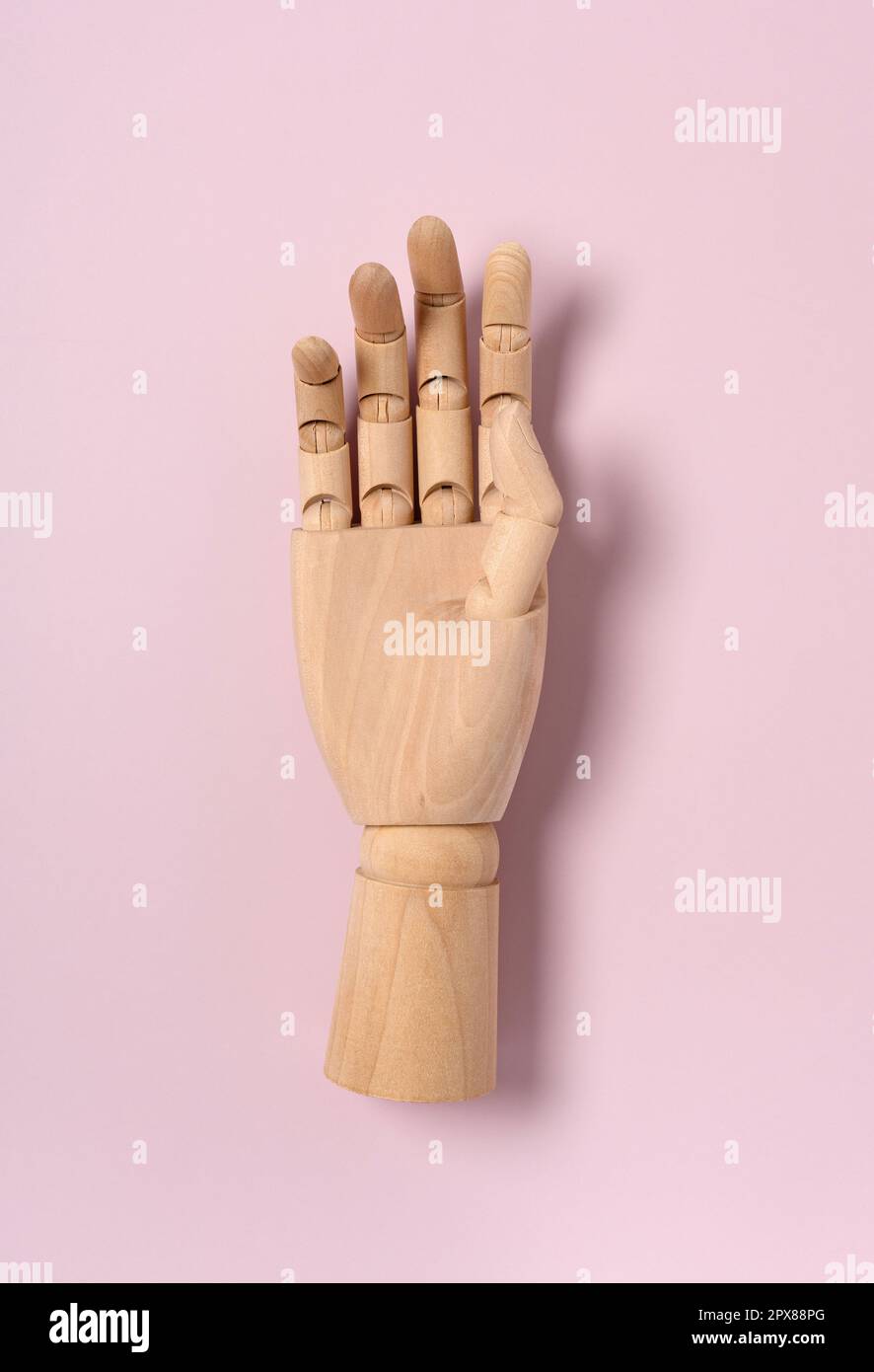 Wooden mannequin hands placed on pink background. View from directly ...