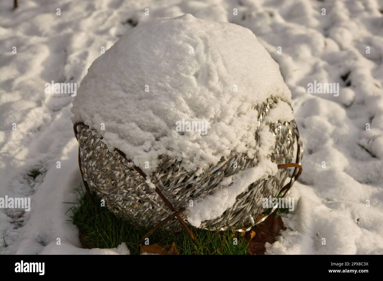 Spherical garden sculpture covered in snow Stock Photo - Alamy