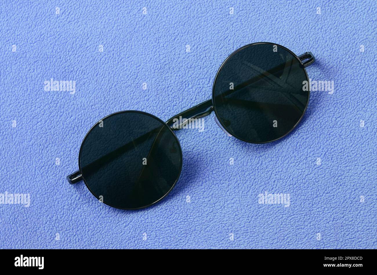 Stylish black sunglasses with round glasses lies on a blanket made of ...