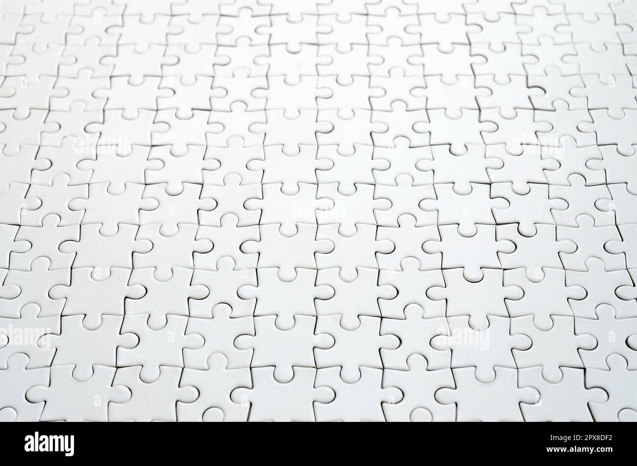 Close up of a white jigsaw puzzle in assembled state in perspective ...