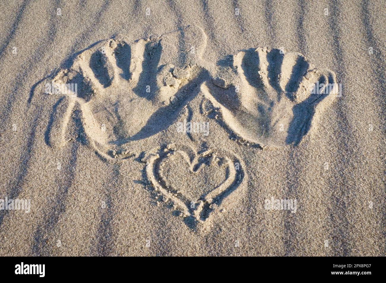 Hand print with heart in sand on beach. Corrugated sand. Still life on ...
