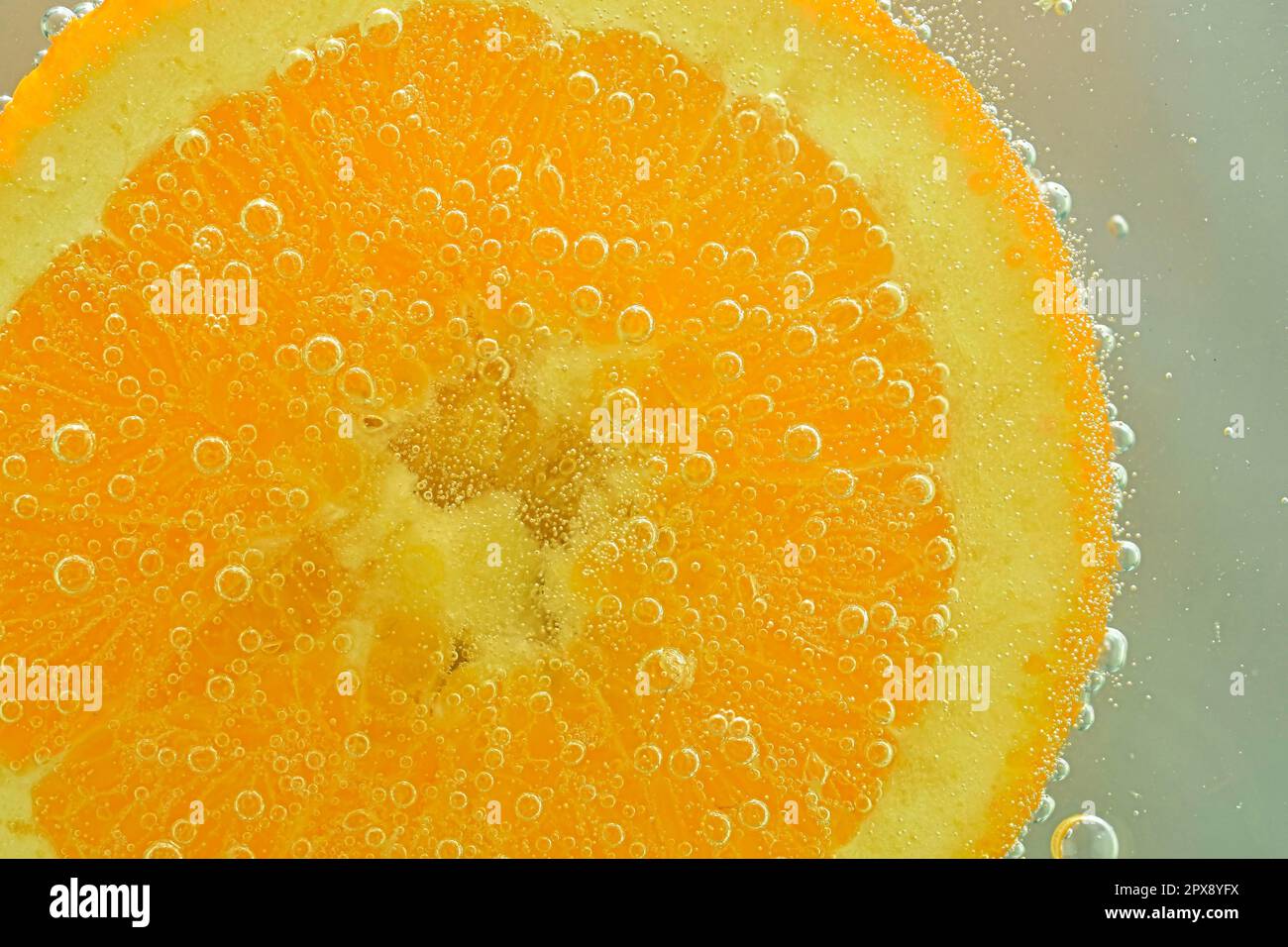 Slice of orange in sparkling water. Orange fruit slice covered by bubbles in carbonated water ...
