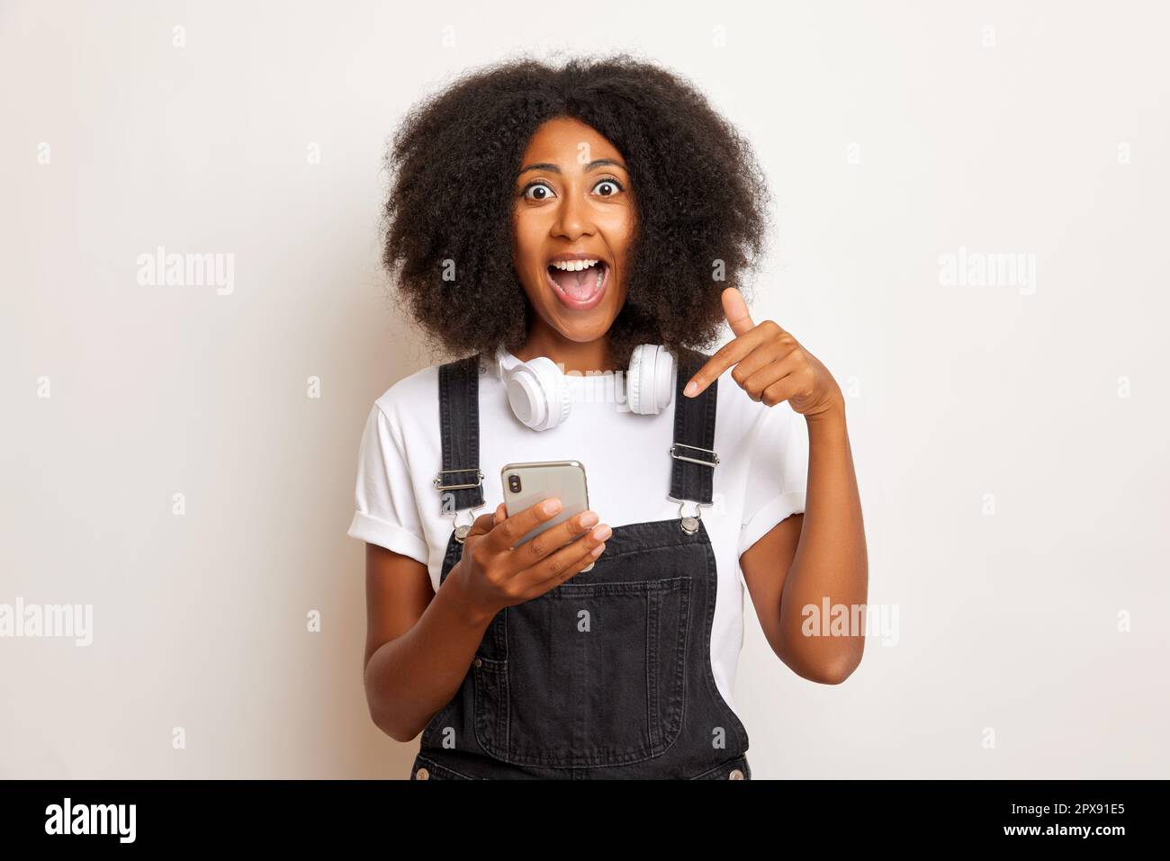 Overjoyed curly haired young ethnic woman with surprised expression ...