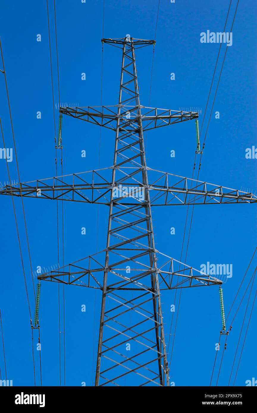 Tower with high-voltage energy transmission wires against the blue sky ...