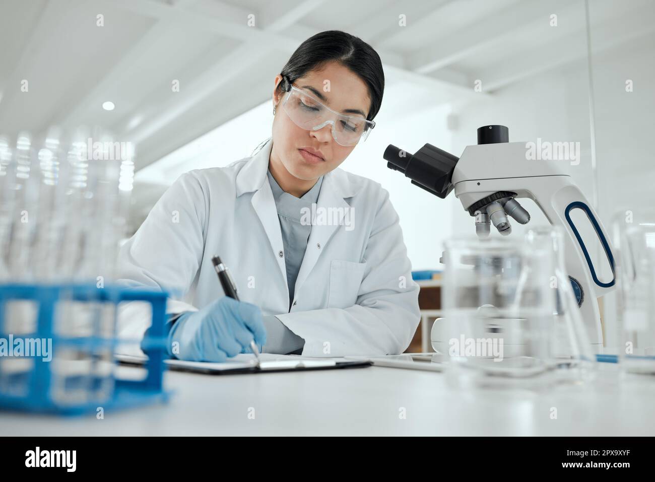 Proving my hypothesis correct. a young woman making notes in her lab ...