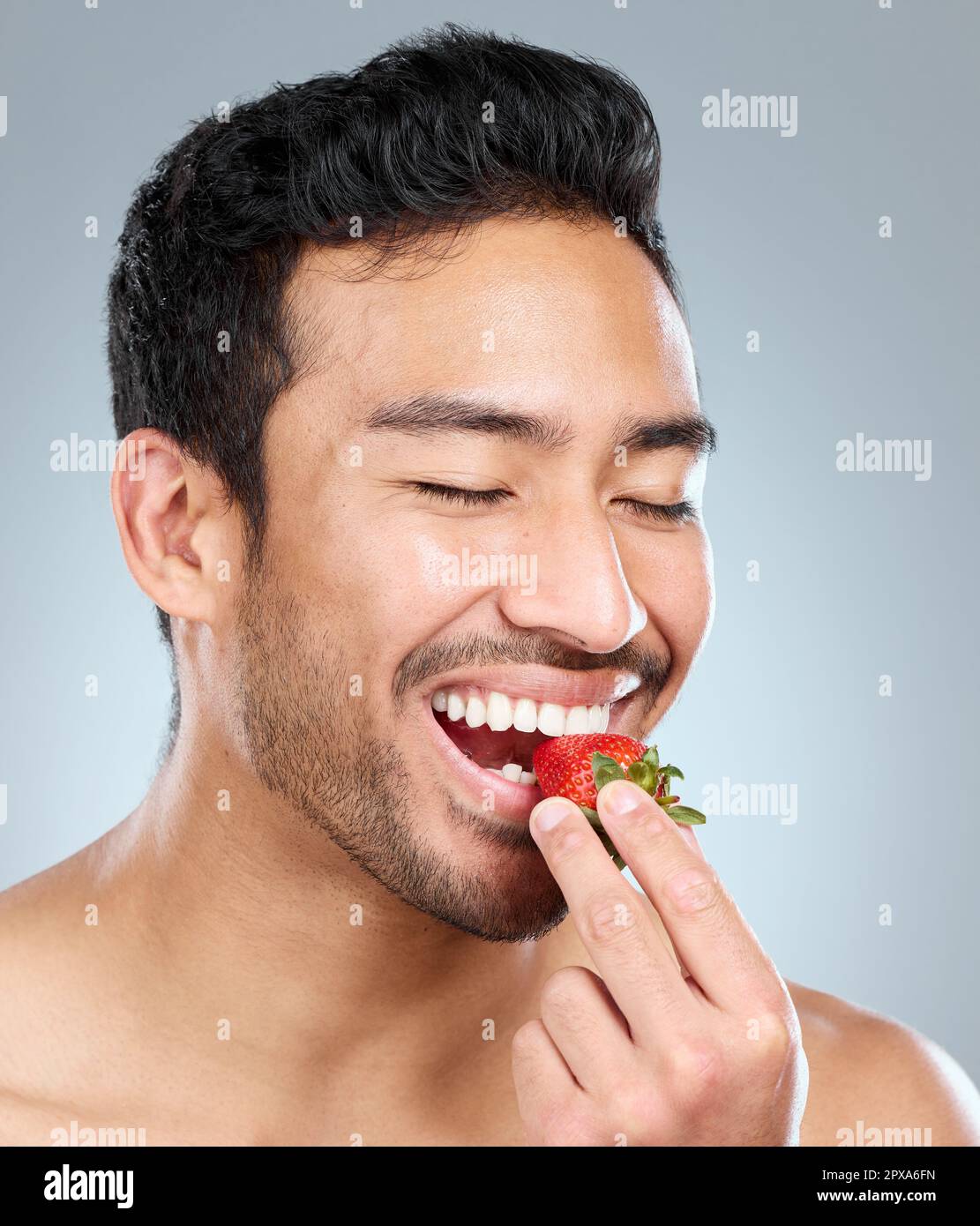 Strawberries are simply irresistible. a man taking a bite of a ...
