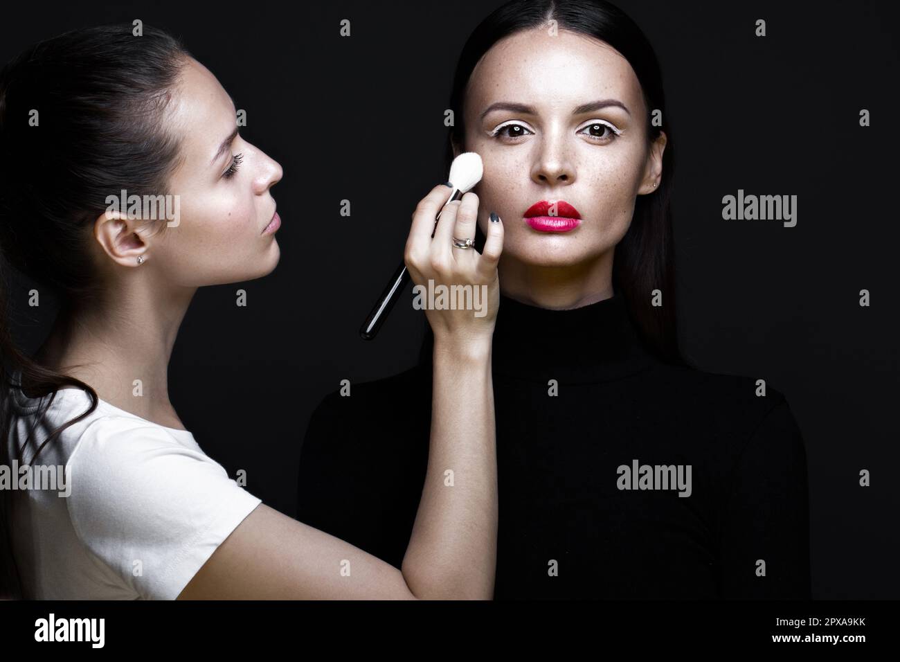 Two beautiful girls on a photo shoot to apply makeup to the face ...
