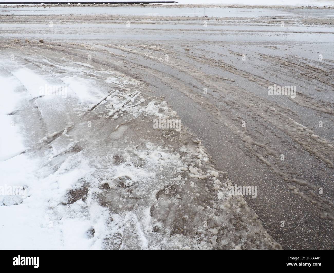 Roadside with a snowdrift. Difficult driving conditions. Wet slippery ...