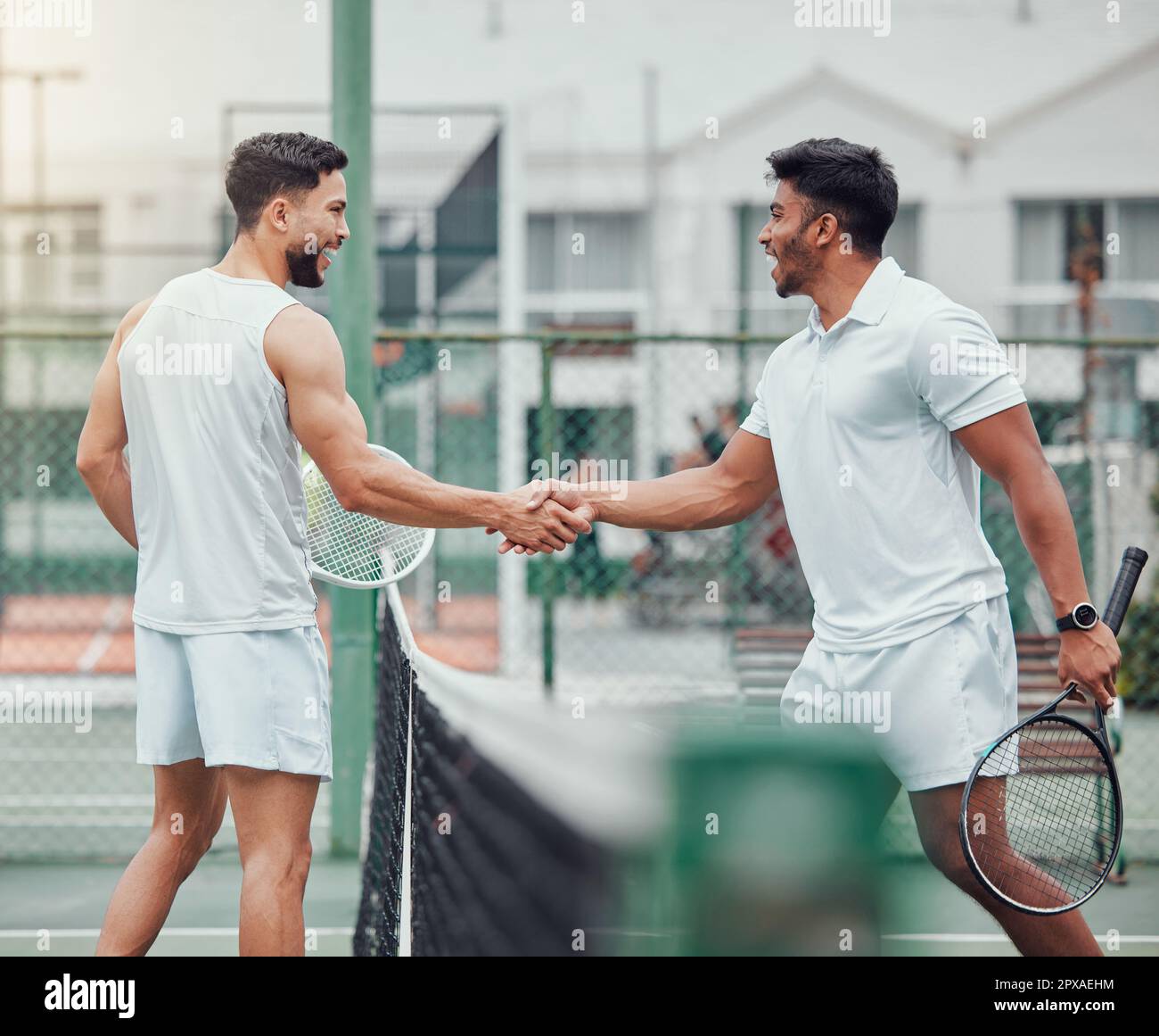Two ethnic tennis players shaking hands before playing court game ...